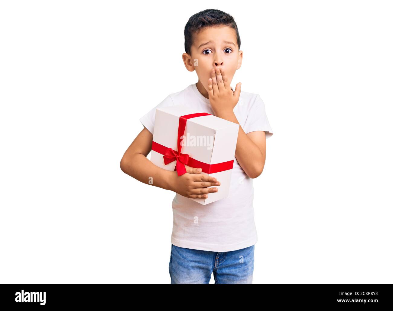 Little cute boy kid holding gift covering mouth with hand, shocked and ...