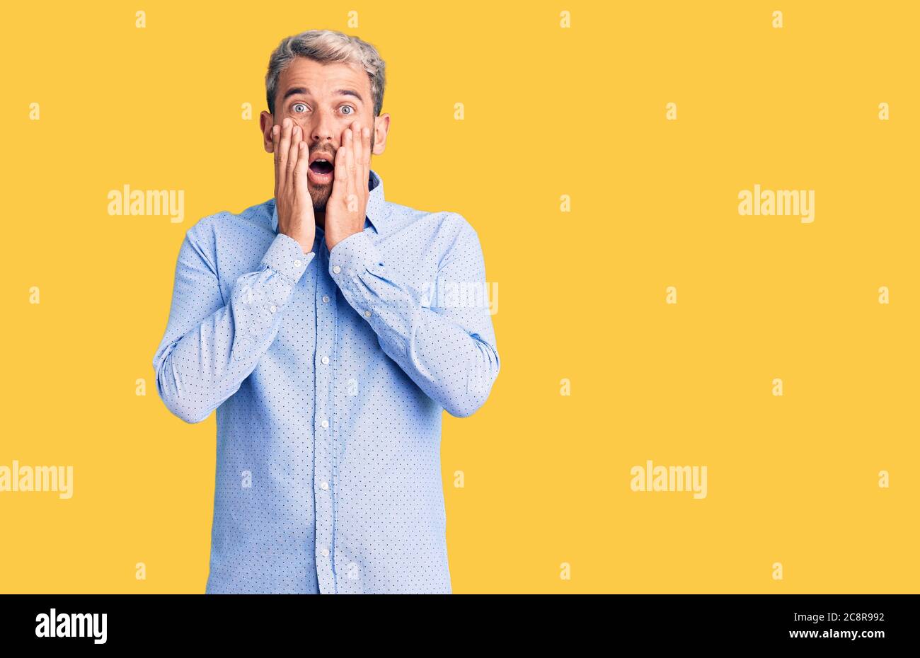 Young handsome blond man wearing elegant shirt afraid and shocked ...