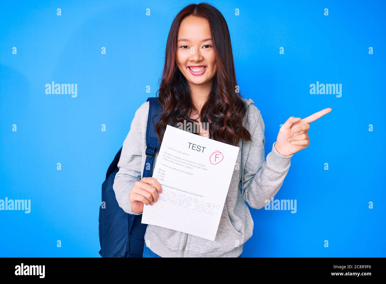 Young beautiful chinese girl showing a failed exam smiling happy ...