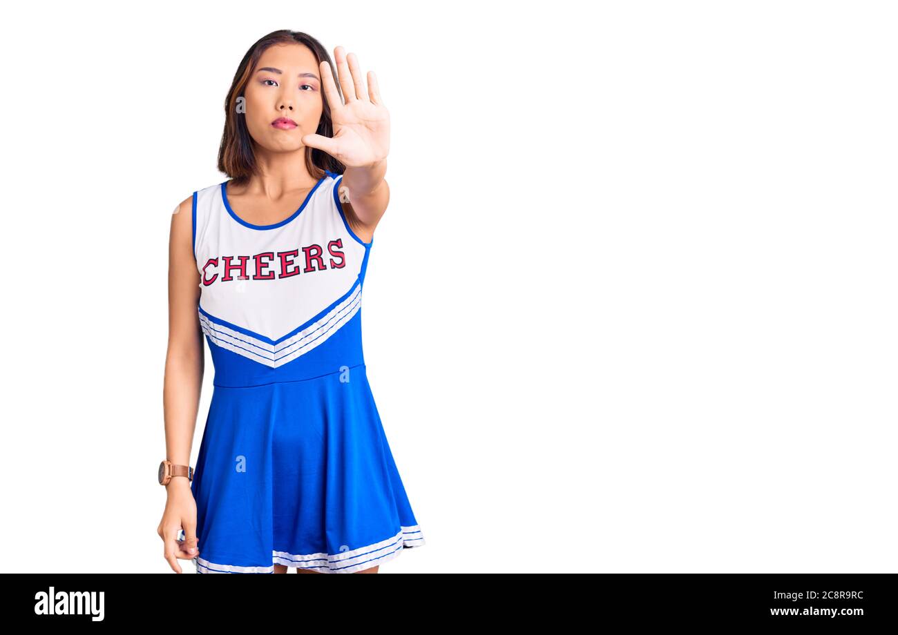 Young beautiful chinese girl wearing cheerleader uniform doing stop ...