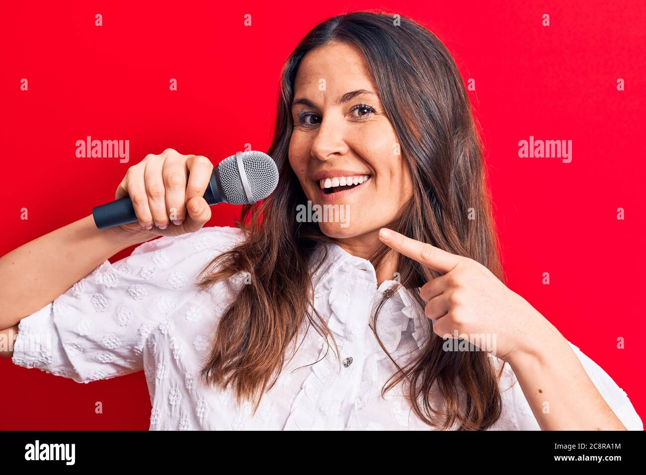 Young beautiful brunette singer woman singing song using microphone ...