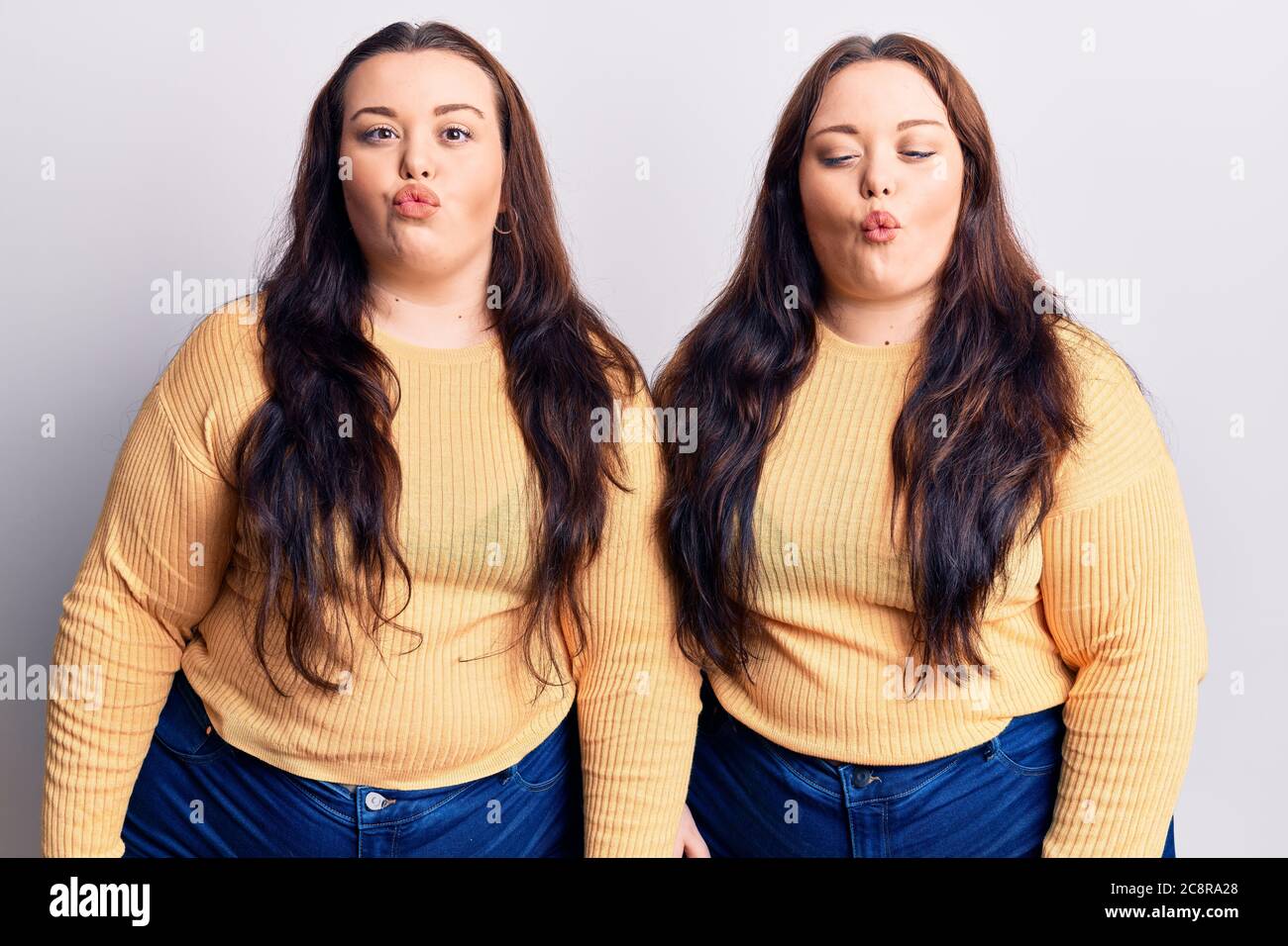 Young plus size twins wearing casual clothes making fish face with lips ...