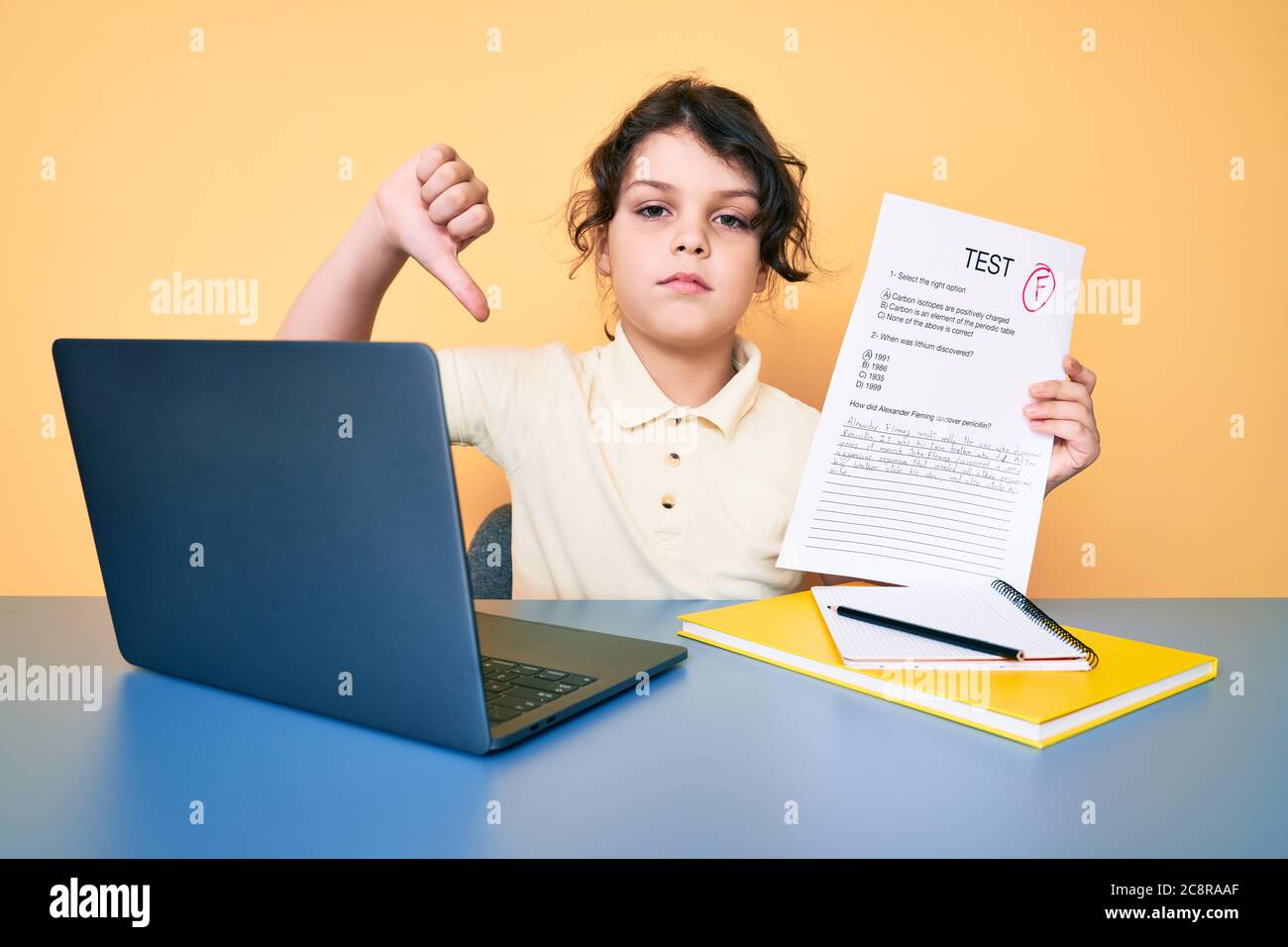 Cute hispanic child showing failed exam sitting on the desk with angry ...