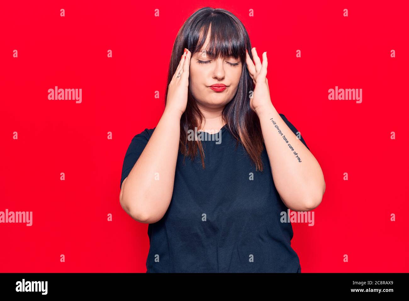 Young plus size woman wearing casual clothes suffering from headache ...