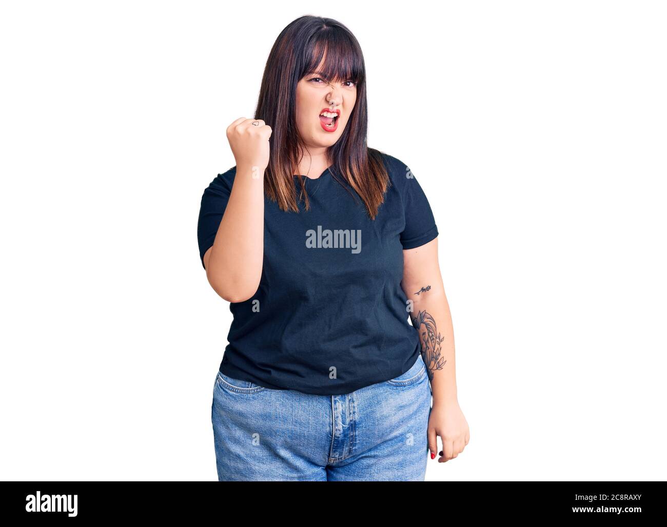 Young plus size woman wearing casual clothes angry and mad raising fist ...