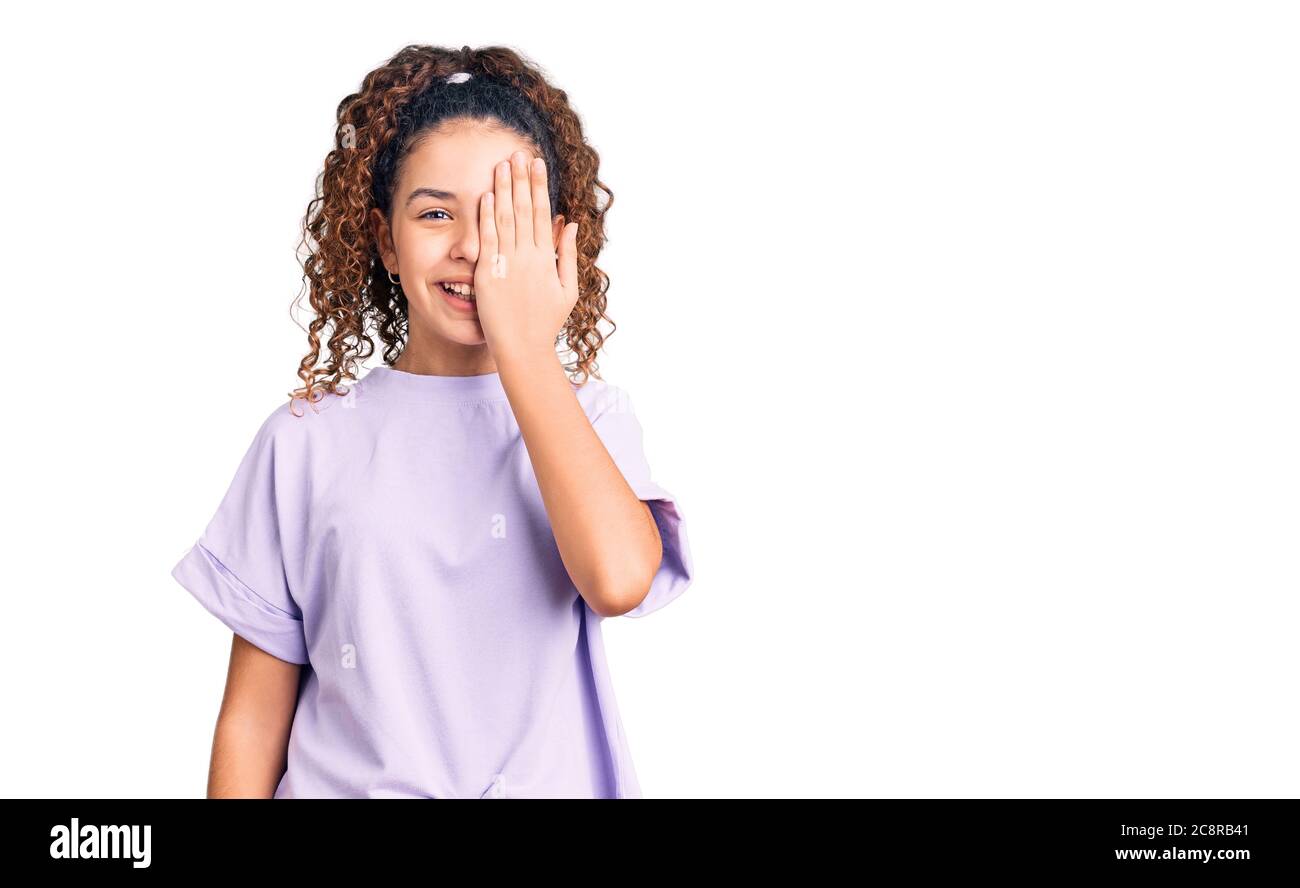 Beautiful kid girl with curly hair wearing casual clothes covering one ...