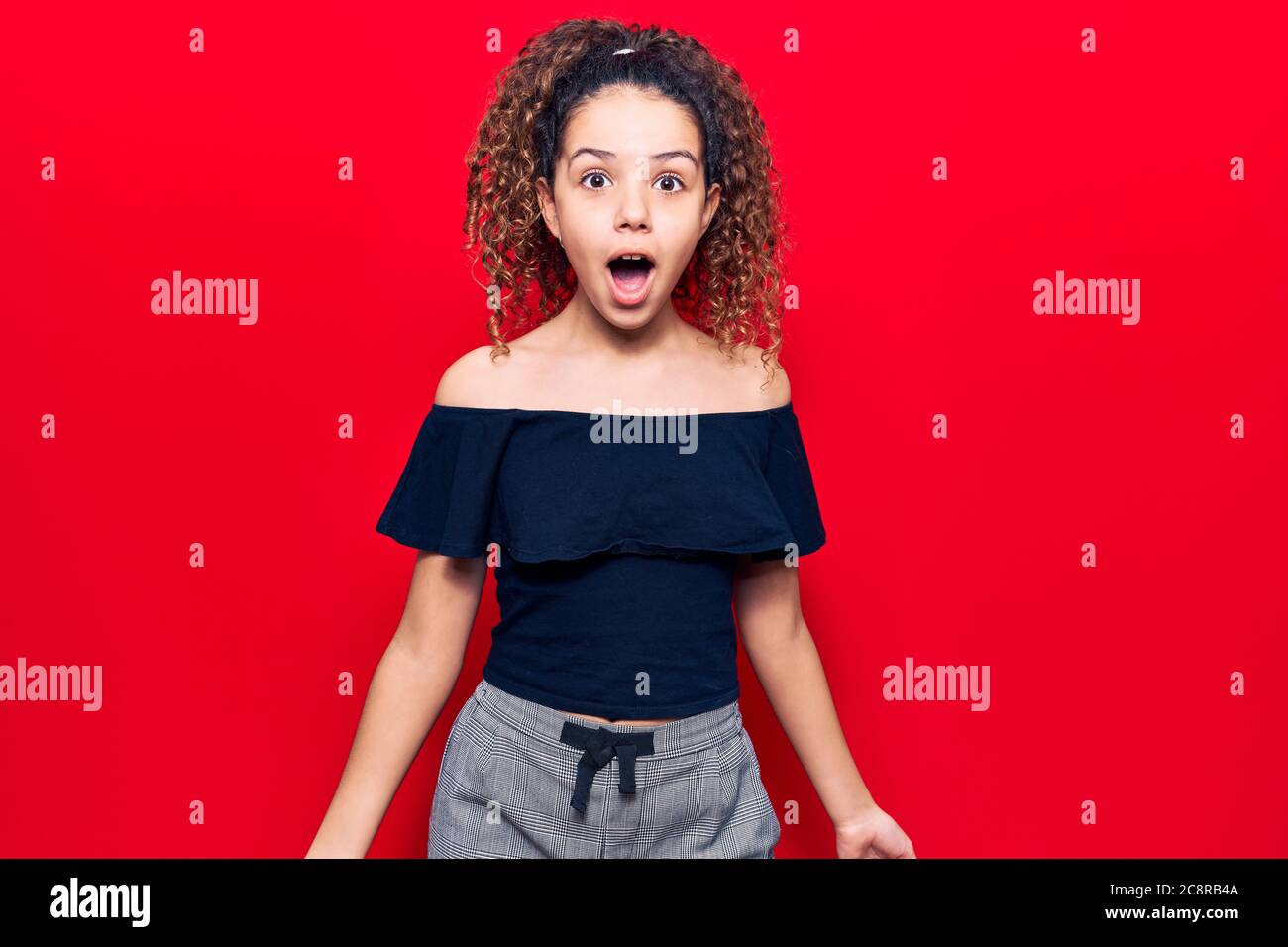 Beautiful kid girl with curly hair wearing casual clothes scared and ...