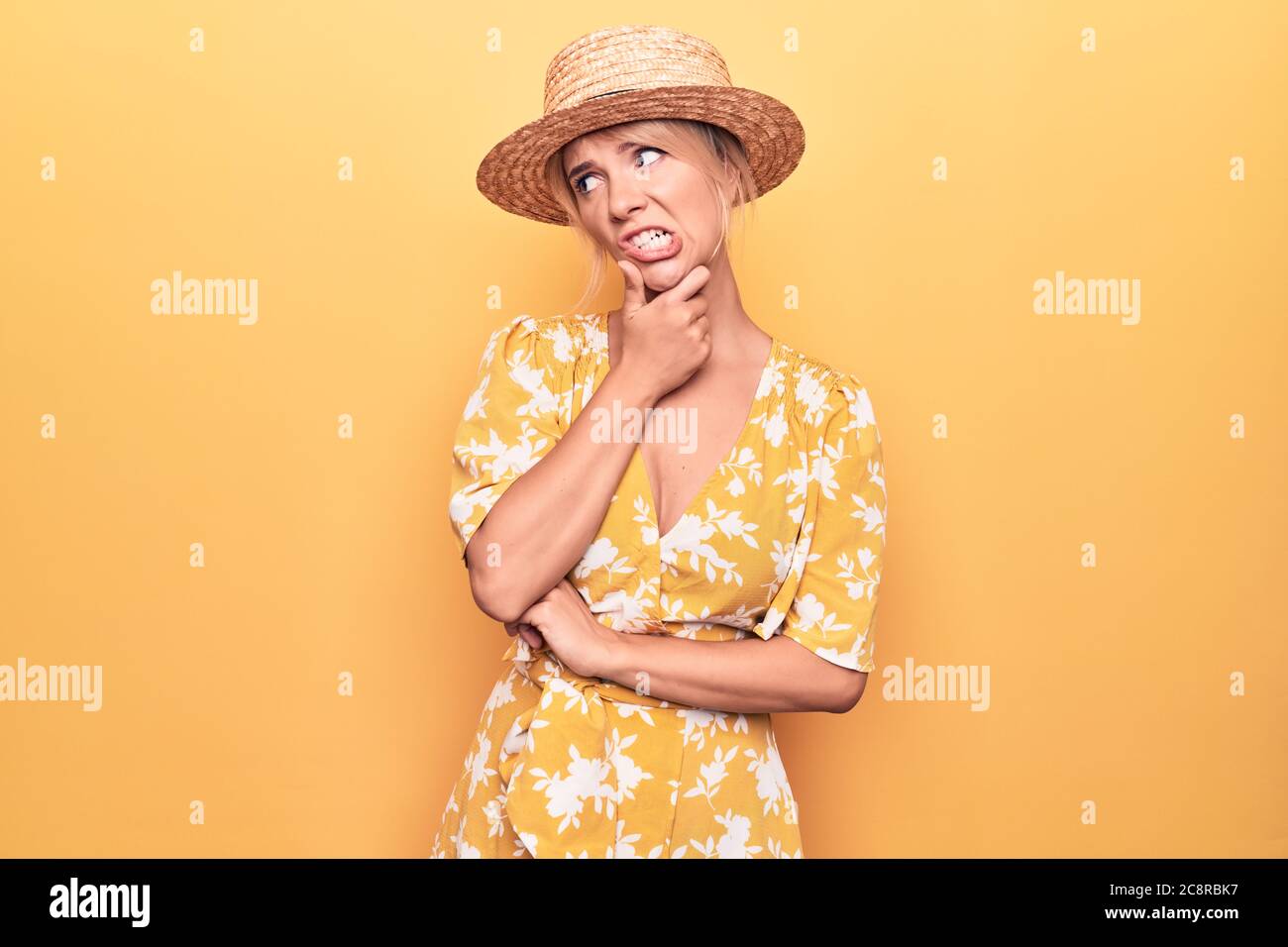 Beautiful blonde woman on vacation wearing summer hat and dress over ...