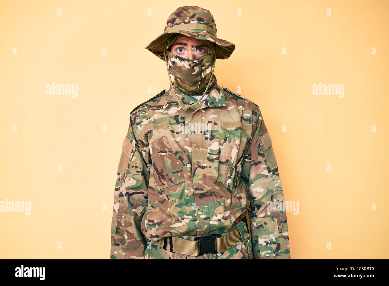 Young handsome man wearing camouflage army uniform and balaclava scared ...