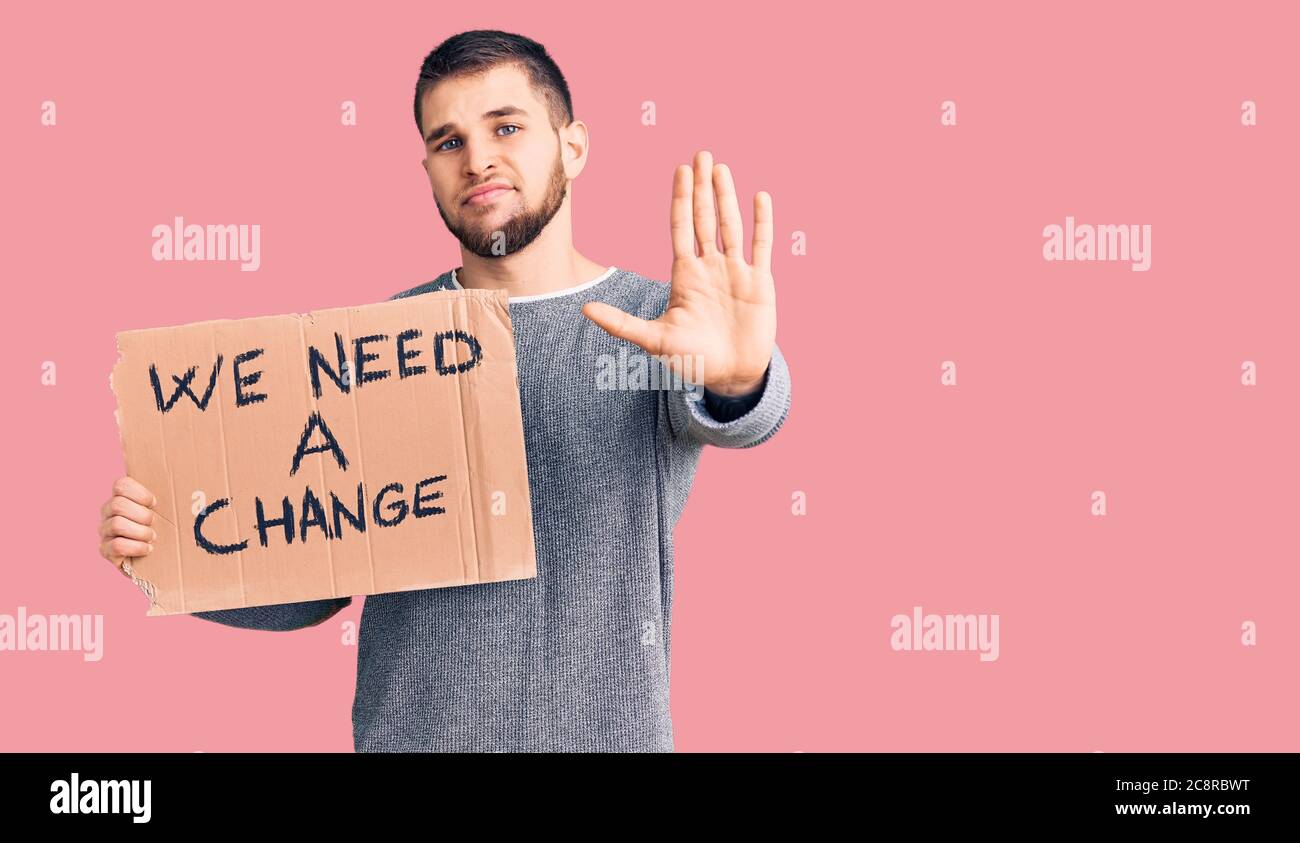 Young handsome man holding we need a change banner with open hand doing ...