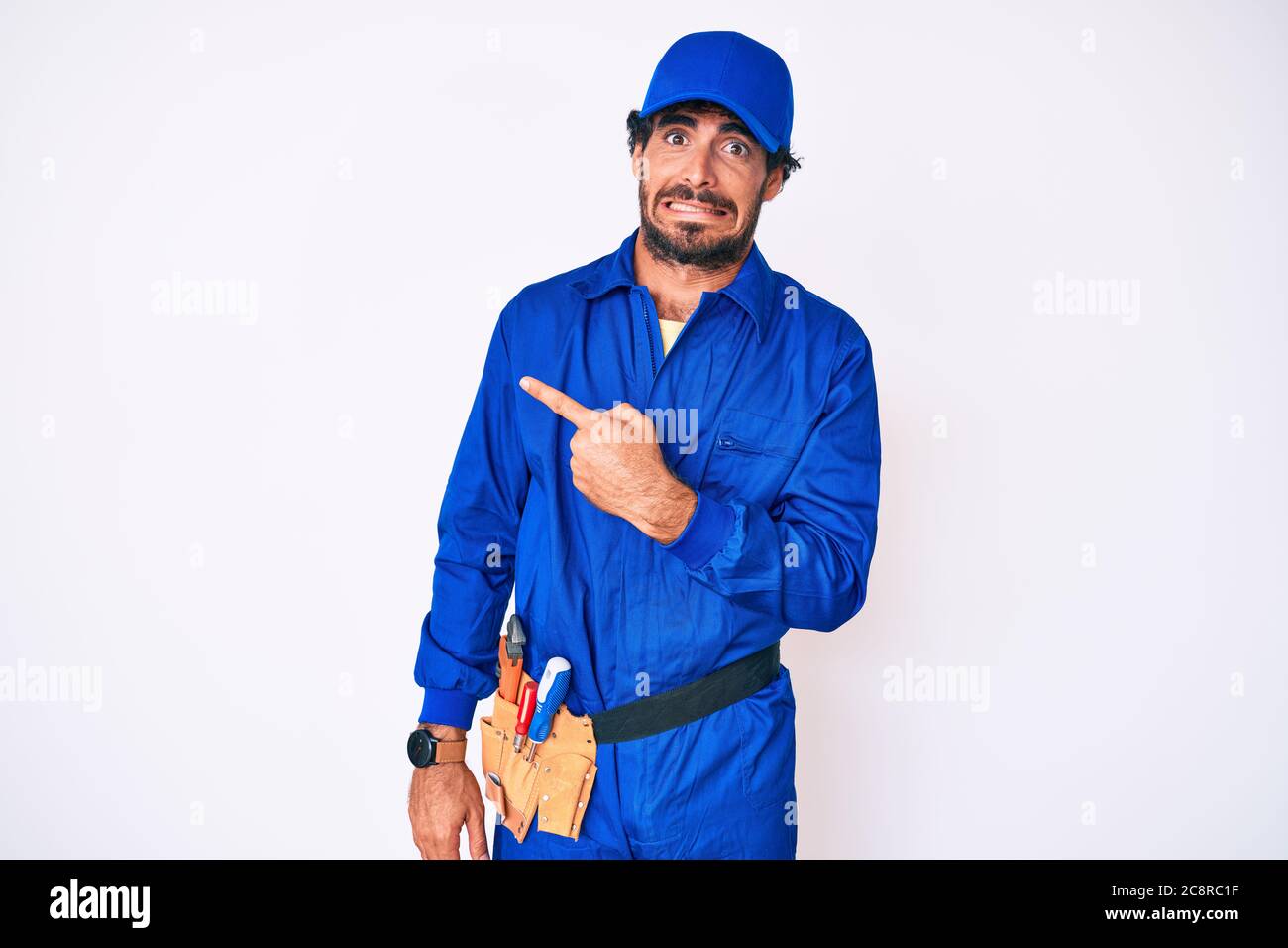 Handsome young man with curly hair and bear weaing handyman uniform ...
