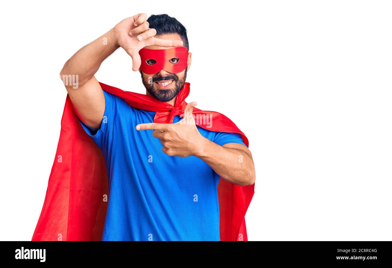 Young hispanic man wearing super hero costume smiling making frame with ...