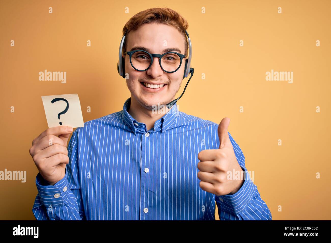 Redhead call center agent man working using headset holding reminder ...