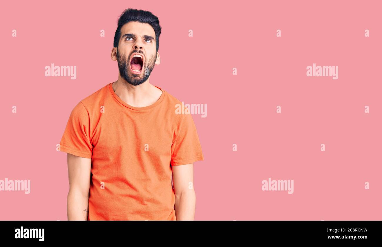 Young handsome man with beard wearing casual t-shirt angry and mad ...