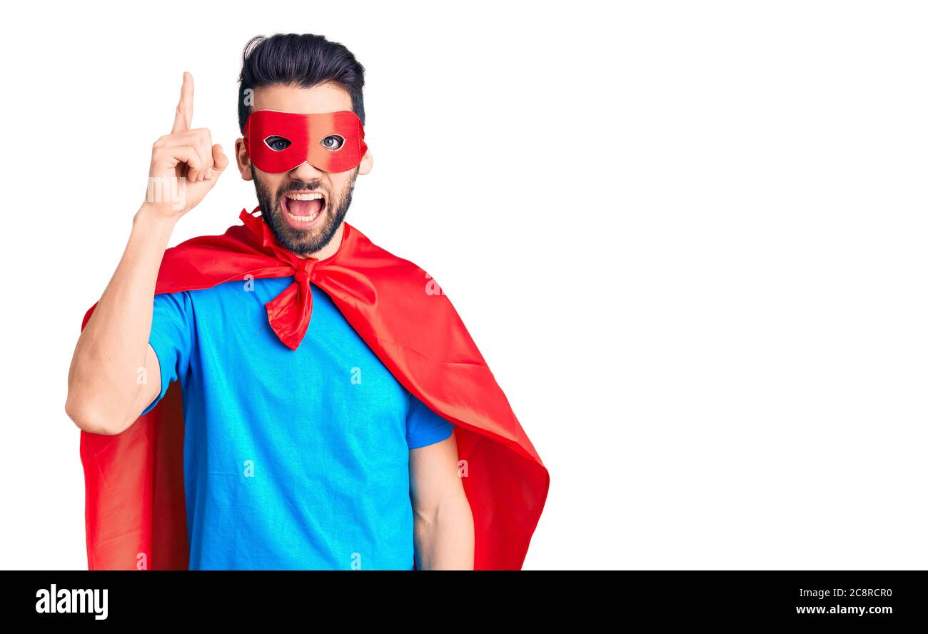 Young handsome man with beard wearing super hero costume pointing ...