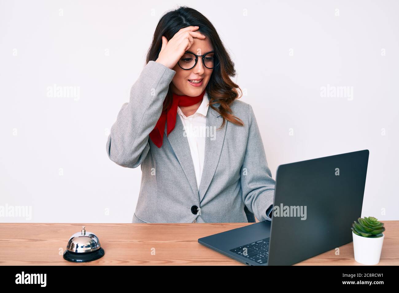 Young beautiful brunette woman working at hotel reception using laptop ...