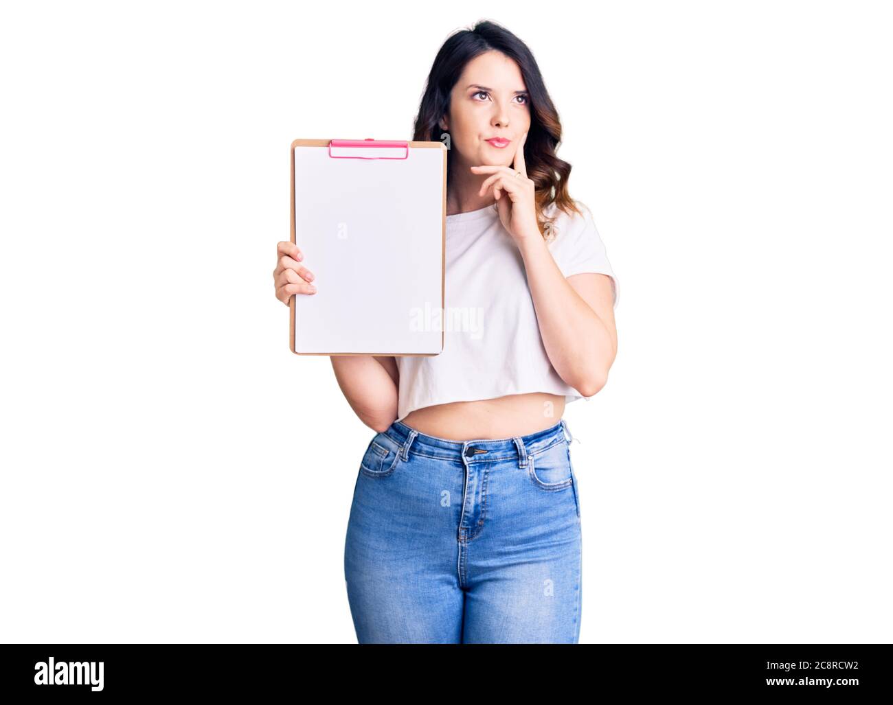 Beautiful young brunette woman holding clipboard with blank space ...