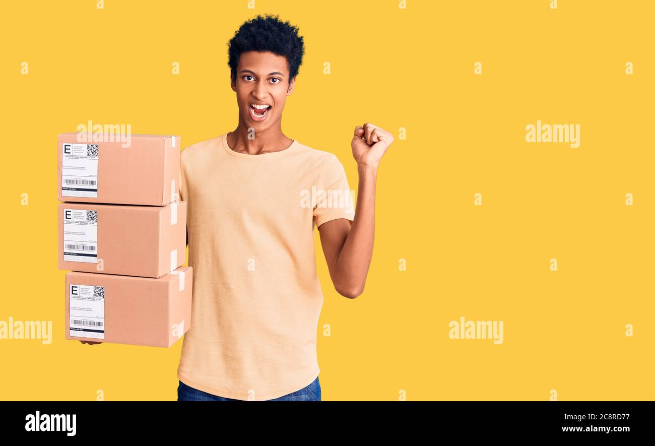 Young african american man holding delivery package screaming proud ...