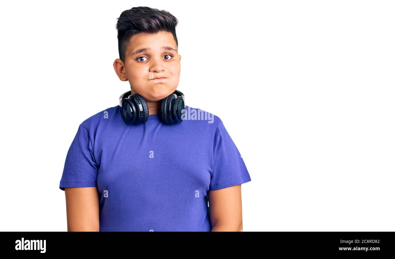 Little boy kid listening to music wearing headphones puffing cheeks ...