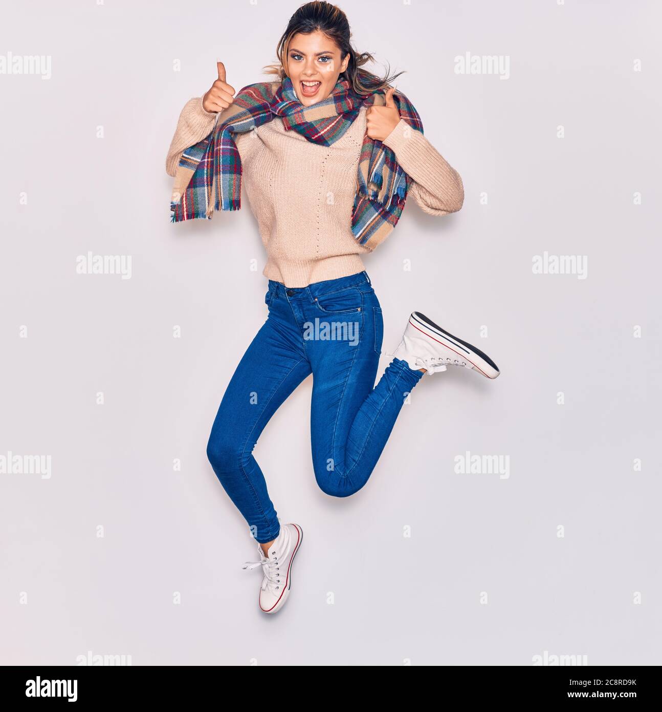 Young beautiful girl wearing winter clothes and scarf smiling happy ...