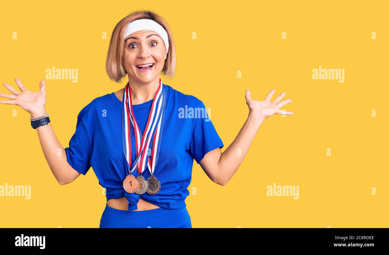 Young blonde woman wearing winner medals celebrating victory with happy ...