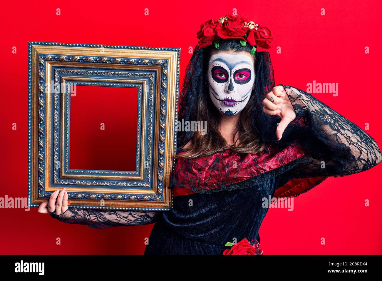 Young woman wearing day of the dead costume holding empty frame with ...