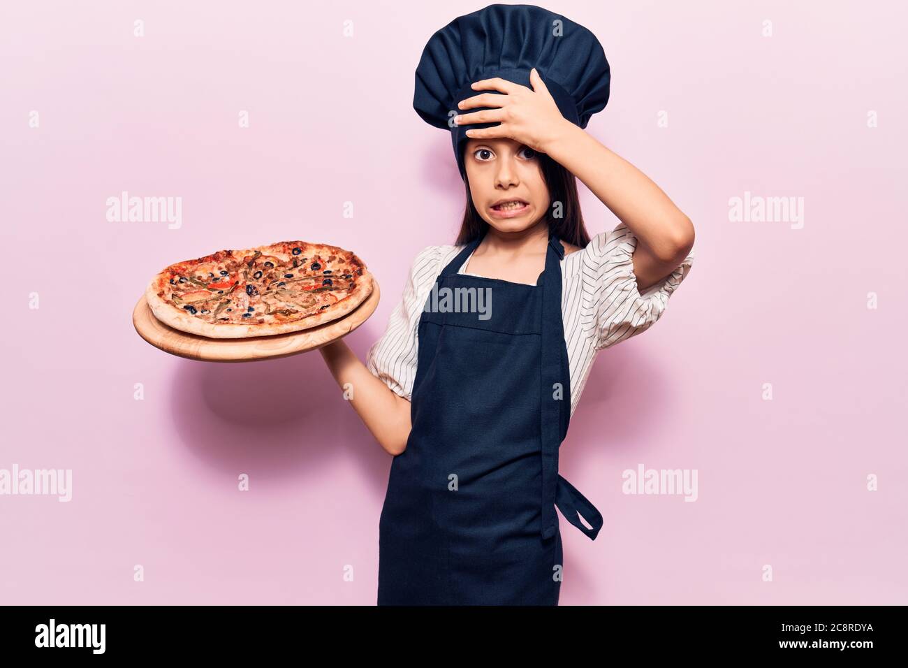 Beautiful child girl wearing cooker uniform holding italian pizza ...