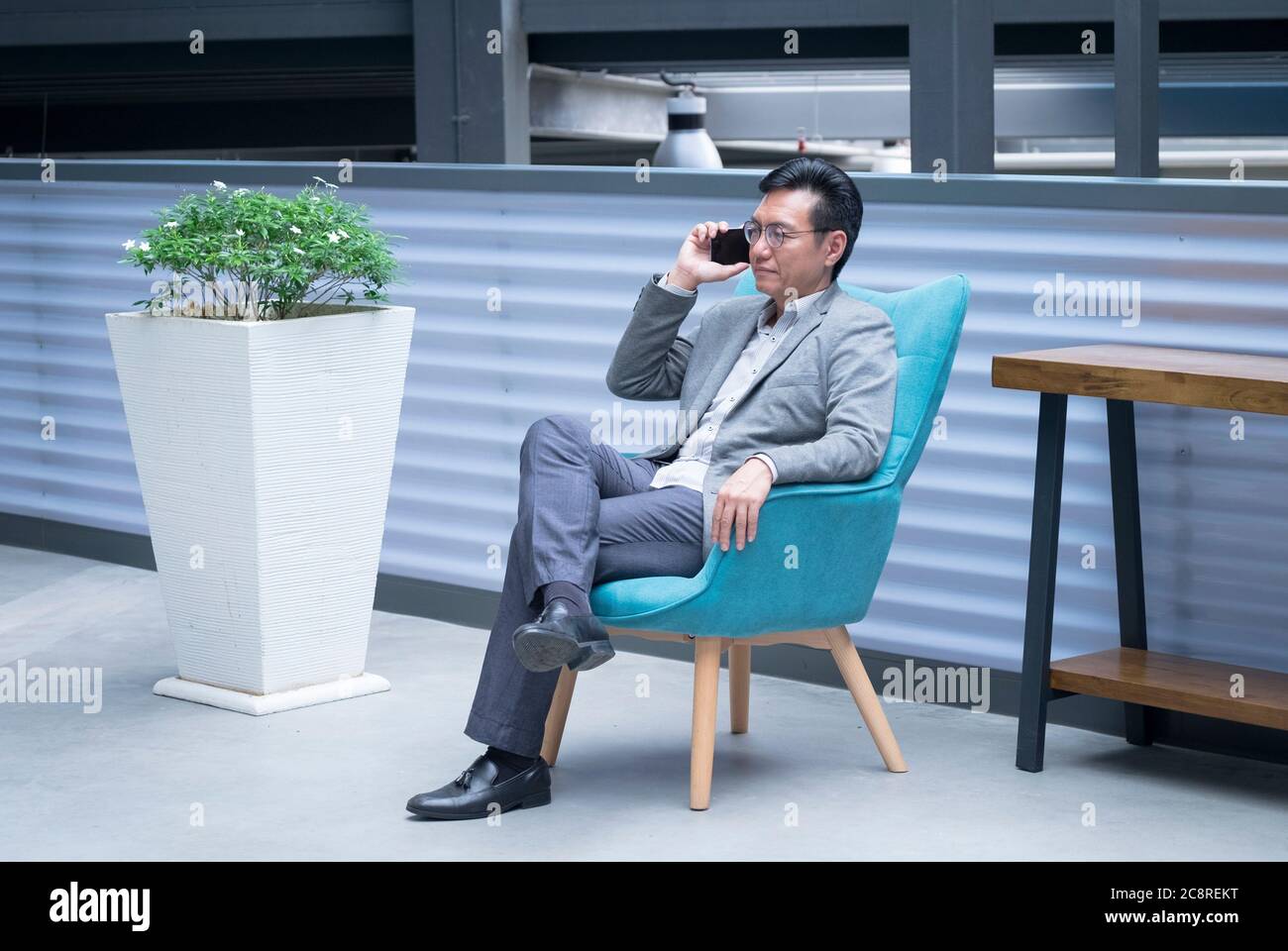 Chinese businessman sitting on a chair and having a phone call via his ...