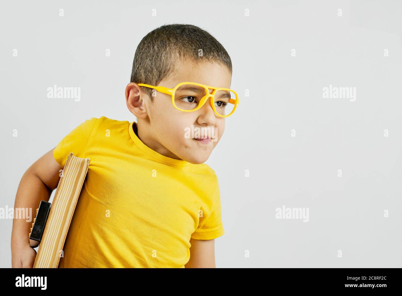Portrait of a funny boy in yellow carrying a big book. Copy space Stock ...
