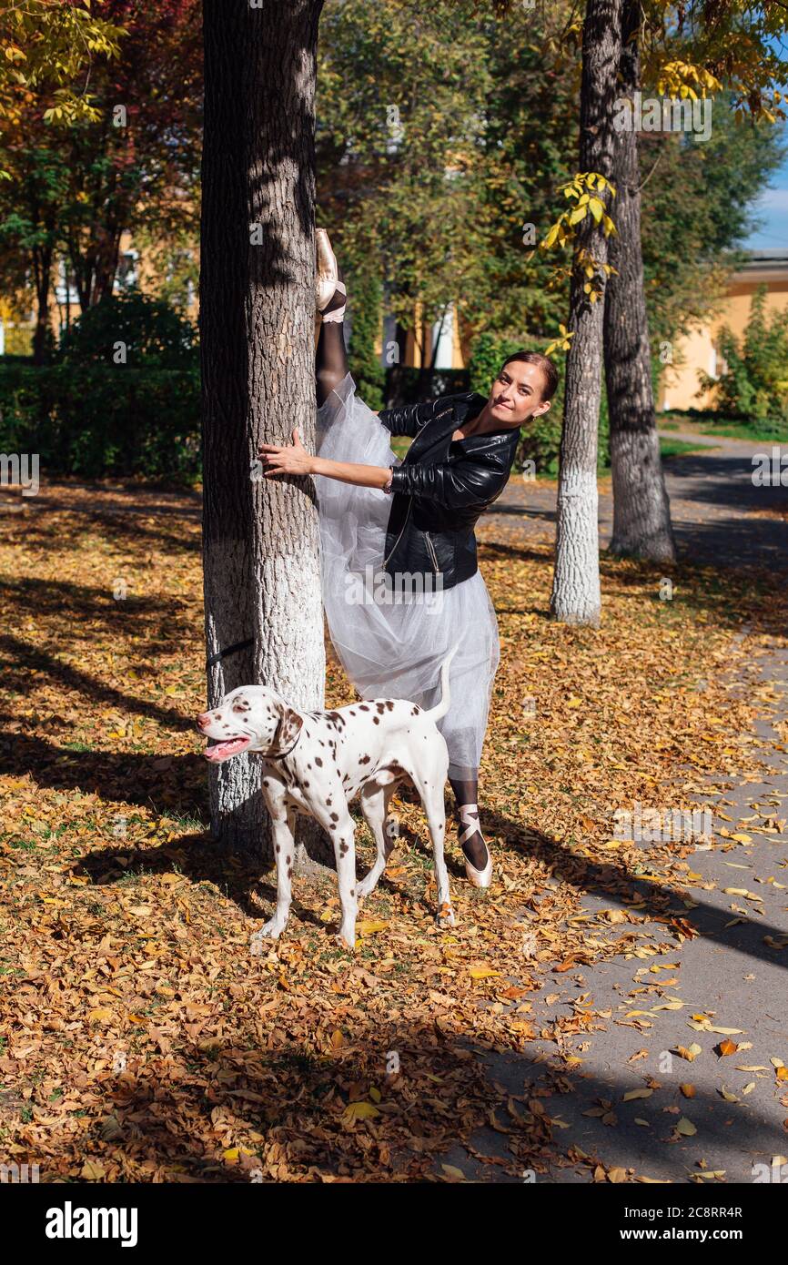 Ballerina with Dalmatian dog in the Park. Woman ballerina in a white ...