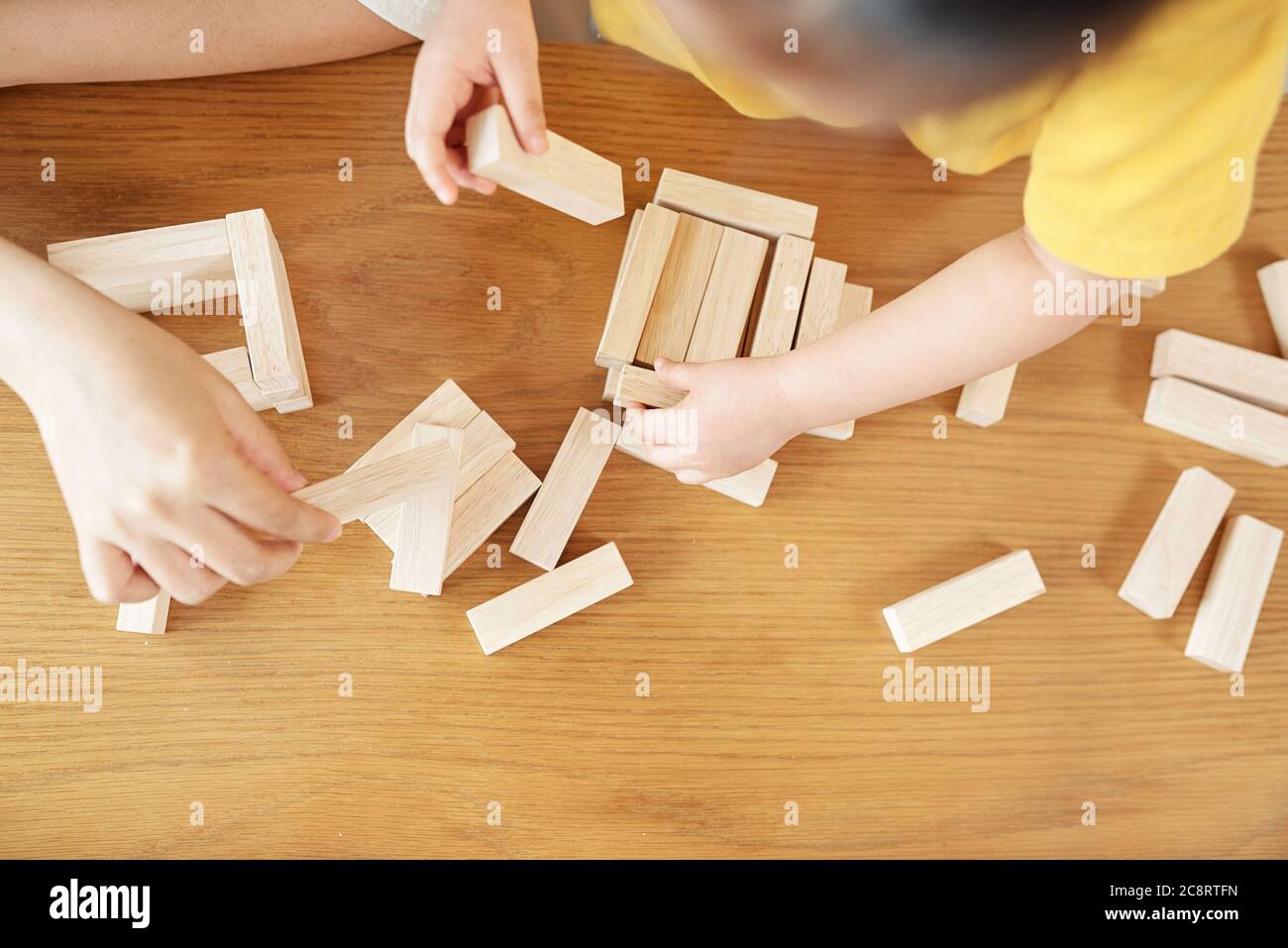 Hands of mother helping little daughter to build tower out of wooden ...