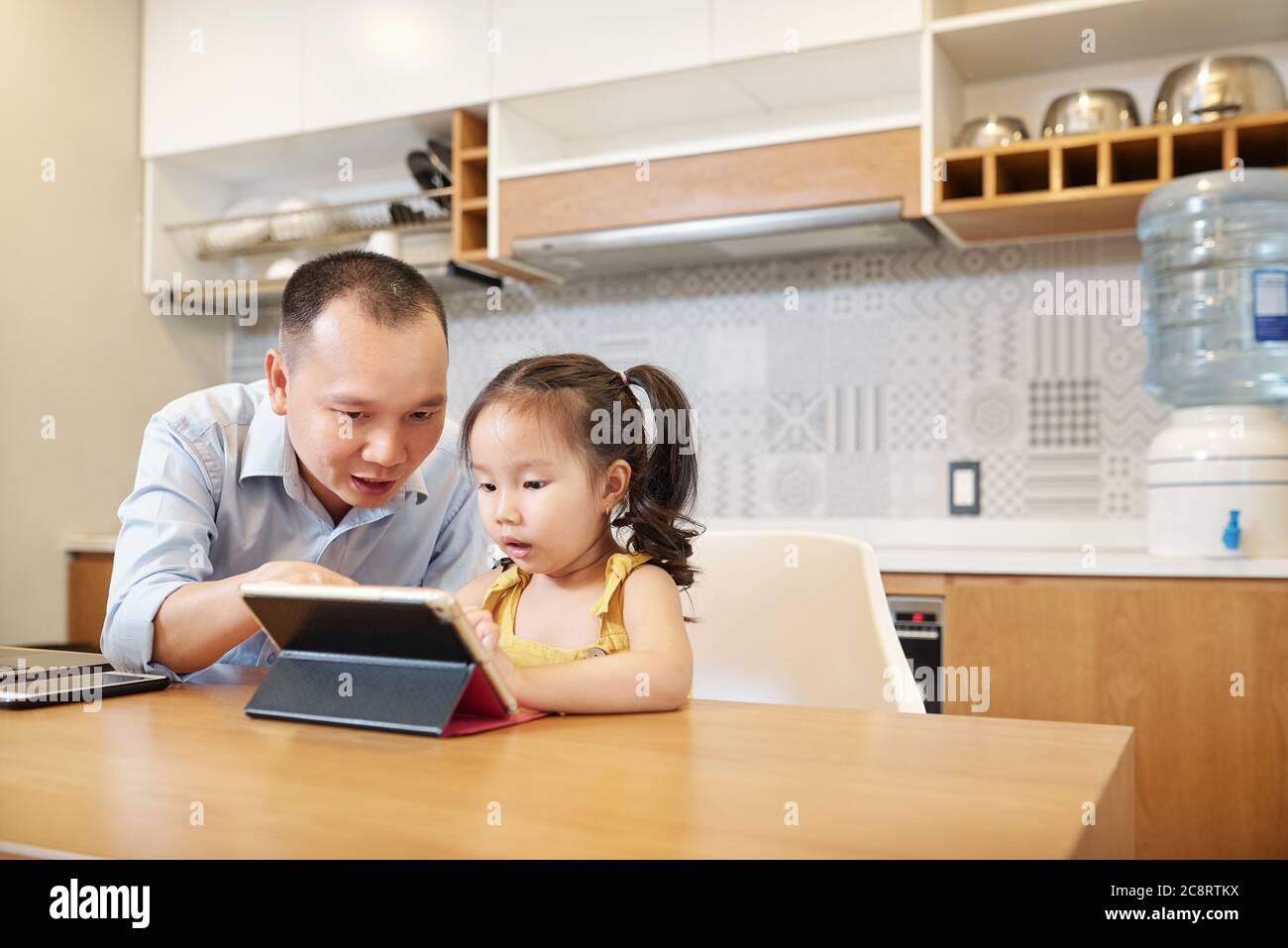 Father helping daughter to solve task in online educational application ...