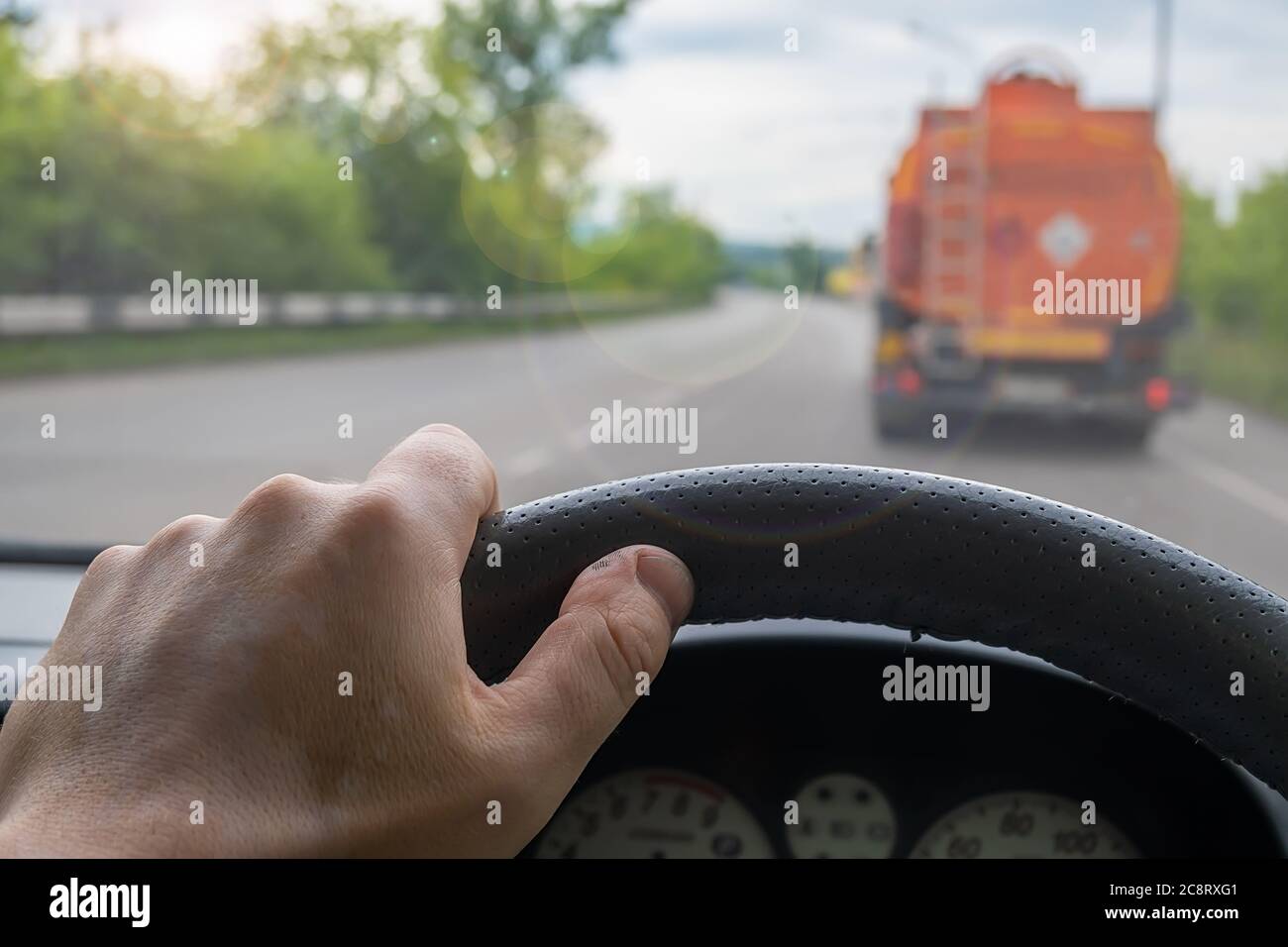 view of the driver hand at the wheel of a car that is driving behind a ...