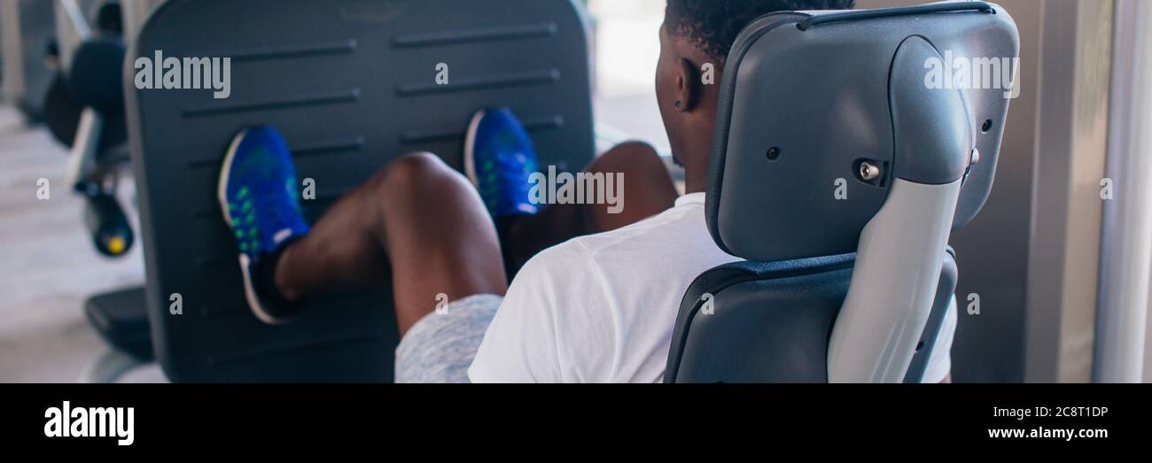 Back view of African American man doing exercise on leg press during ...