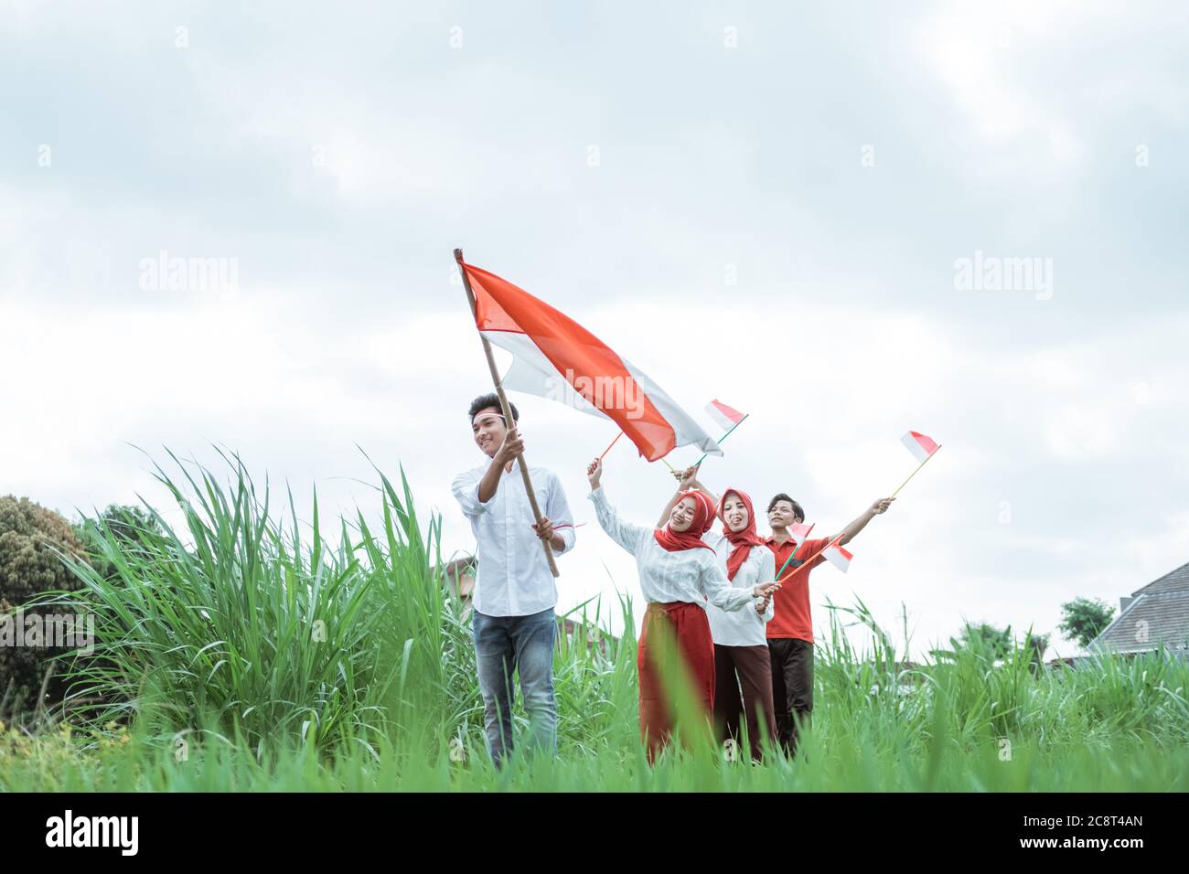 boy in white walking carrying an Indonesian flag with stick and three ...