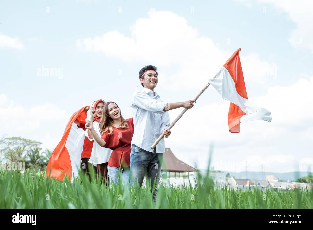 Asian man holds and raises Indonesian flag while following behind his ...