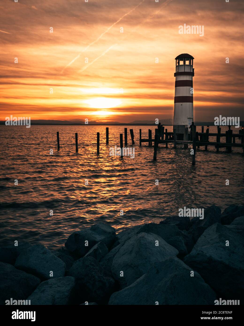 Ocean sunset with lighthouse Stock Photo - Alamy