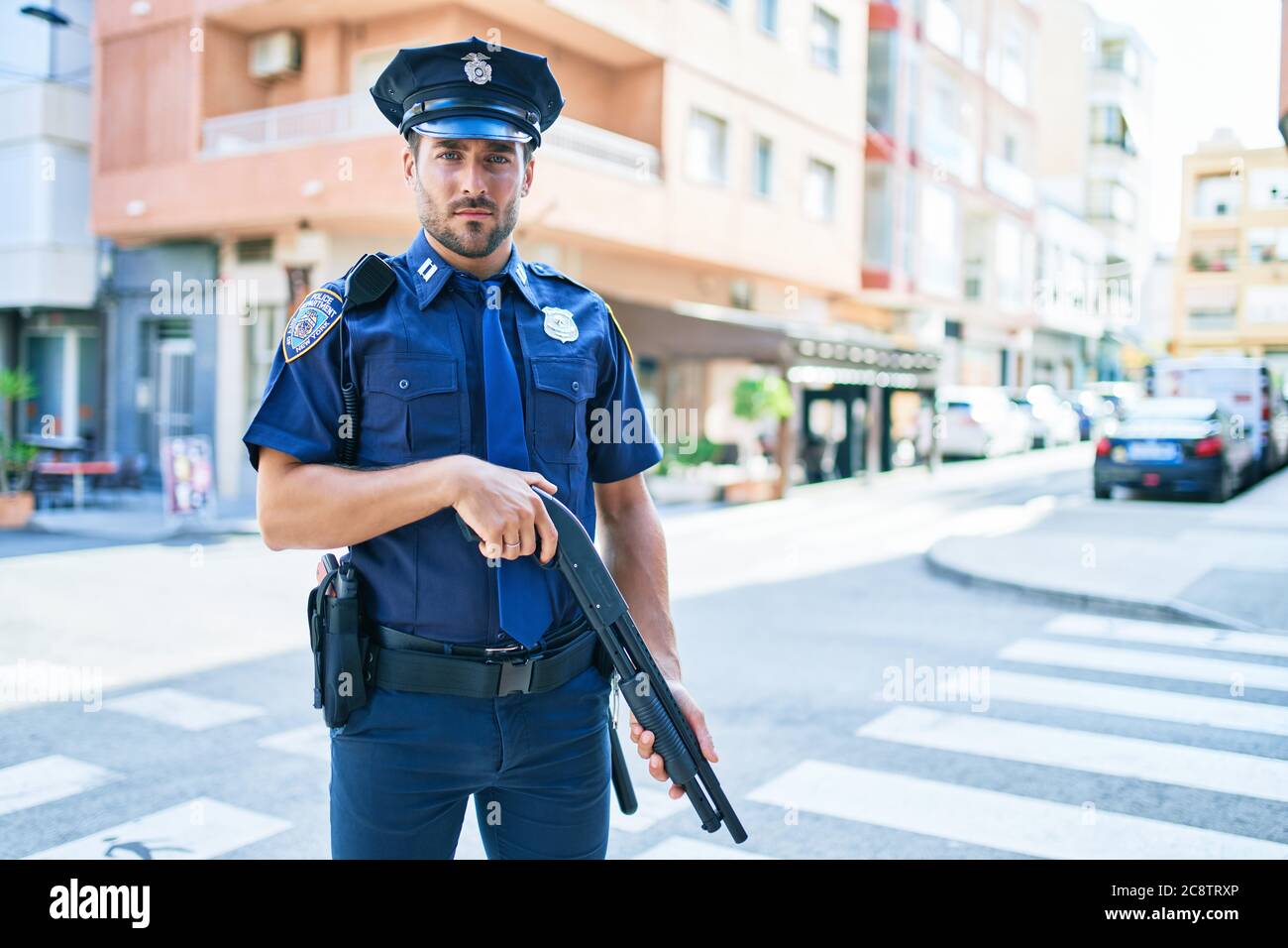 Young handsome hispanic policeman wearing police uniform with serious ...
