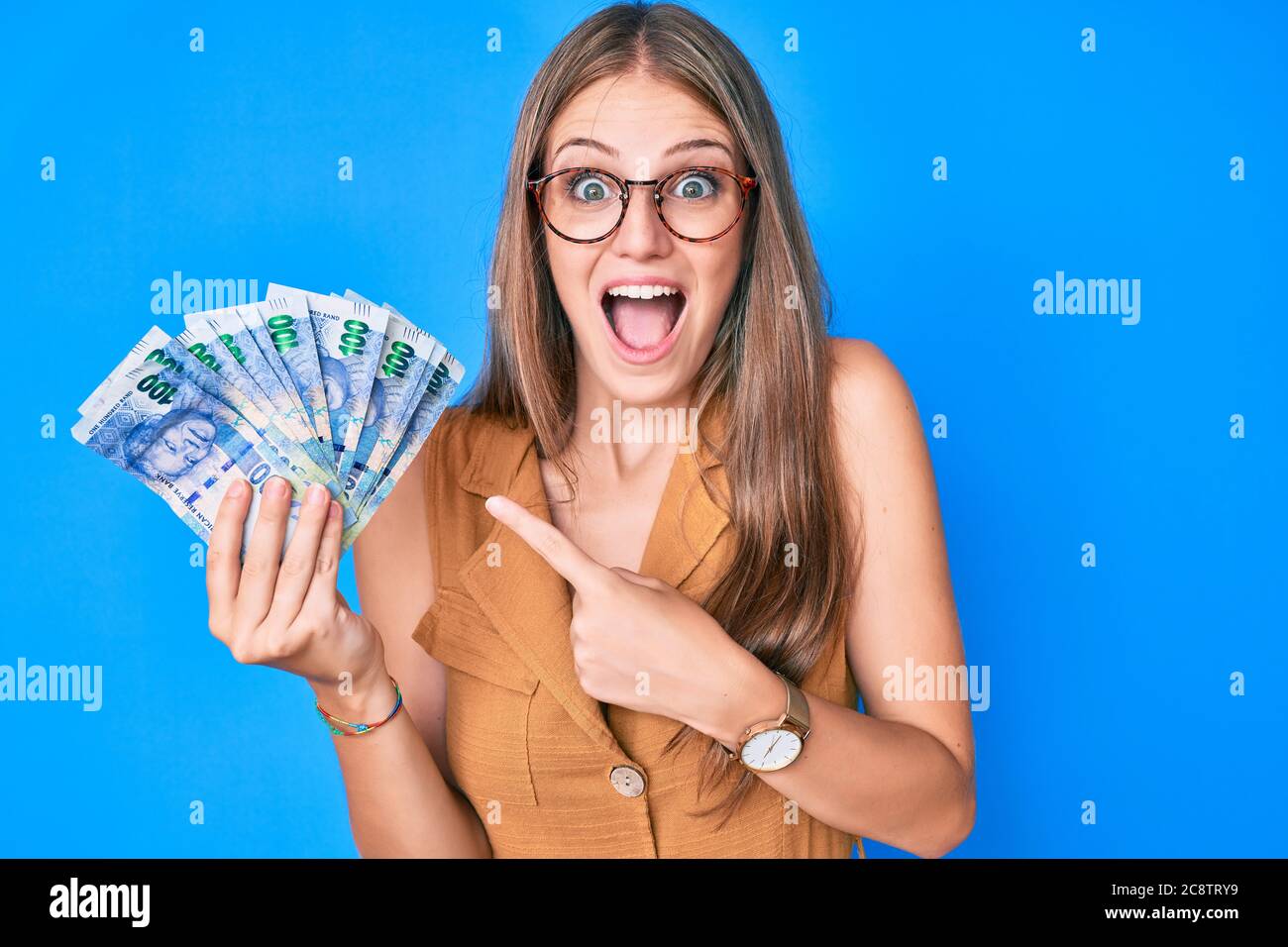 Young blonde girl holding south african rand banknotes celebrating ...