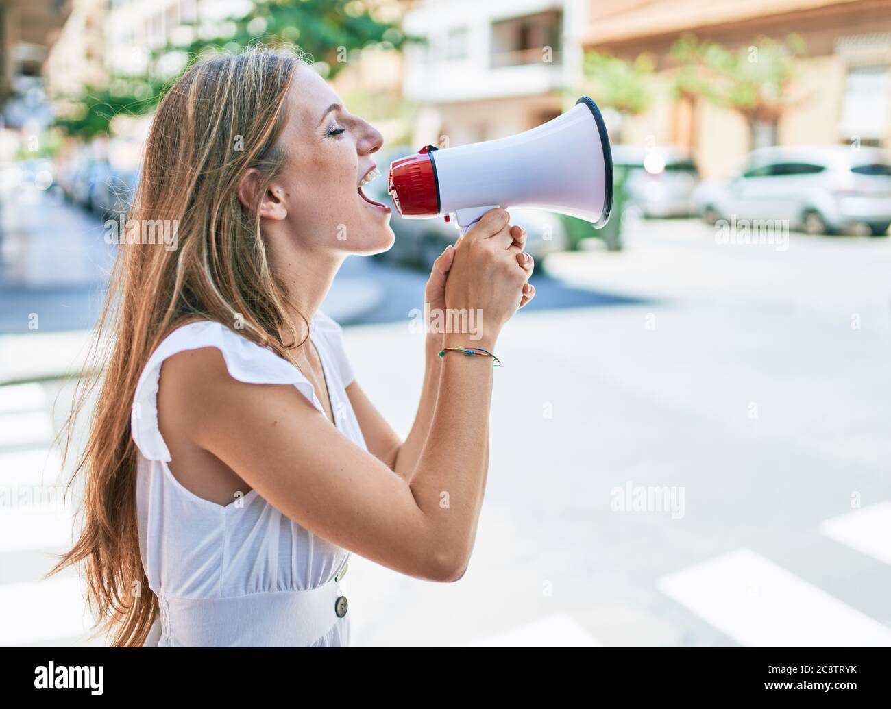 Young caucasian woman screaming using megaphone at the city Stock Photo ...