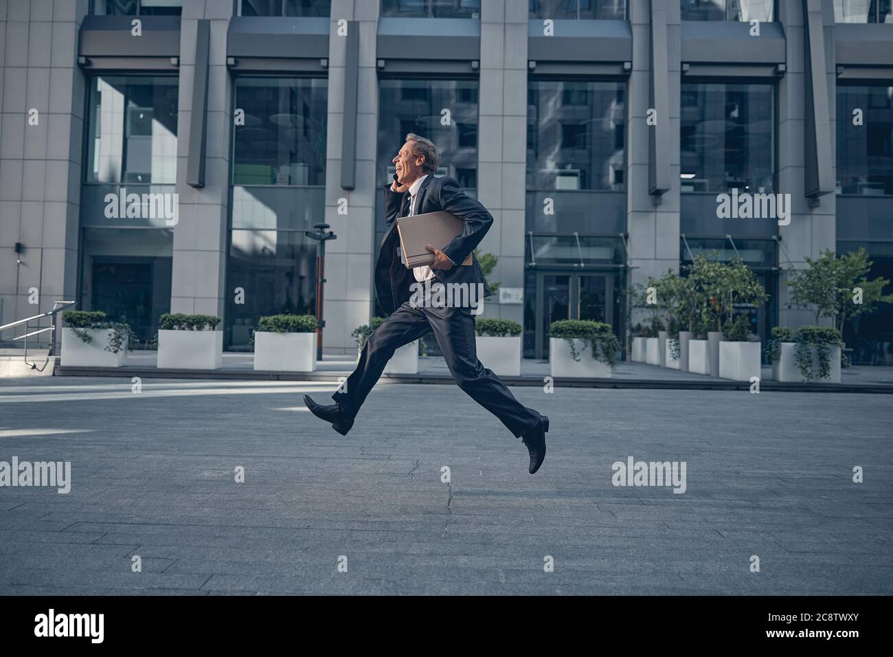 Cheerful man talking on cellphone and running fast on the street Stock ...