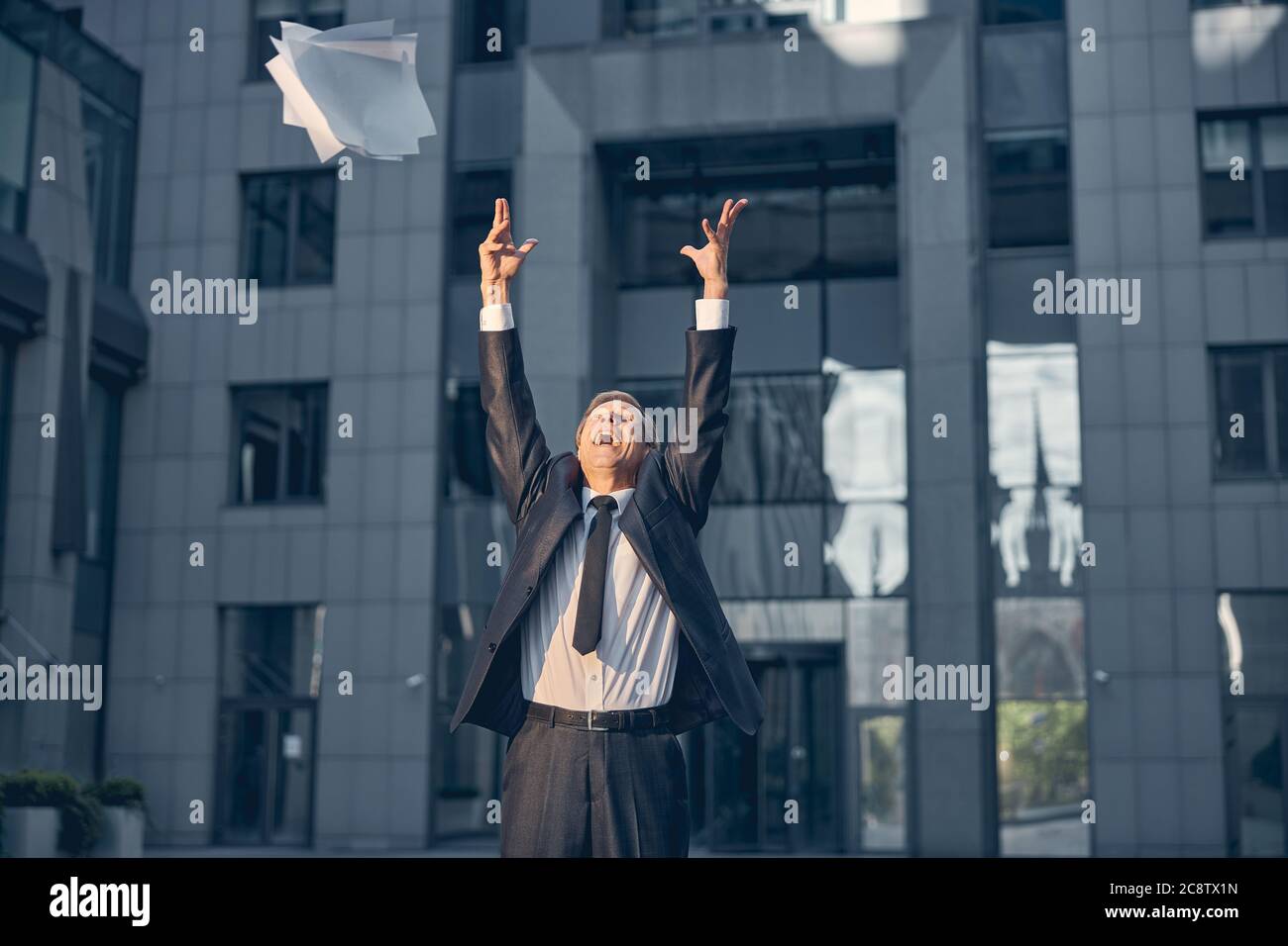 Happy businessman throwing papers in the air Stock Photo - Alamy