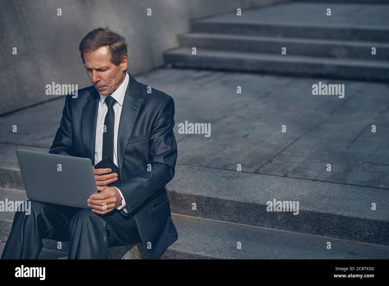 Good-looking businessman using notebook on the street Stock Photo - Alamy