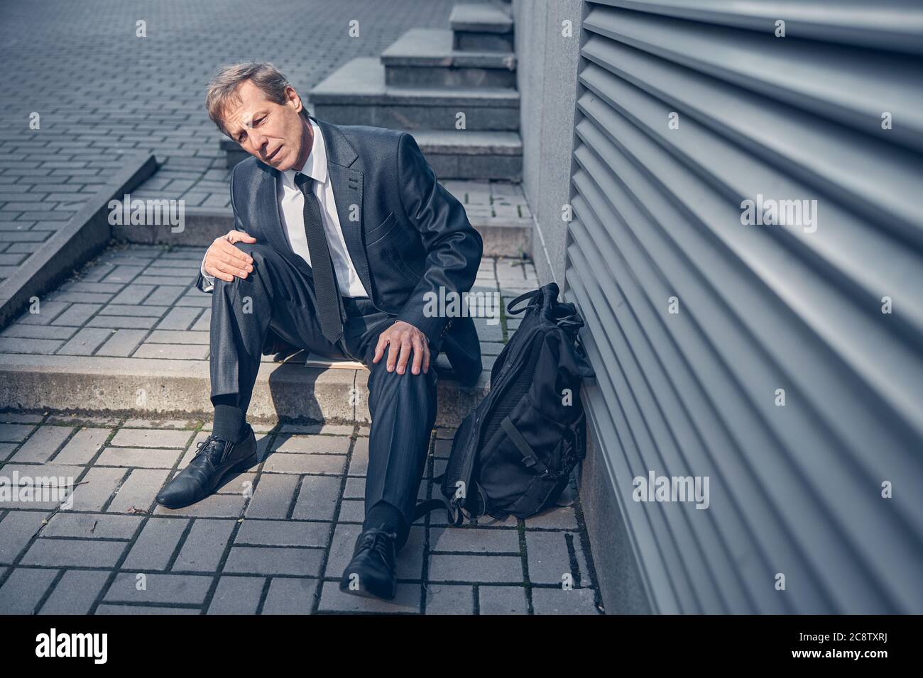 Tired man sitting on steps on the street Stock Photo - Alamy