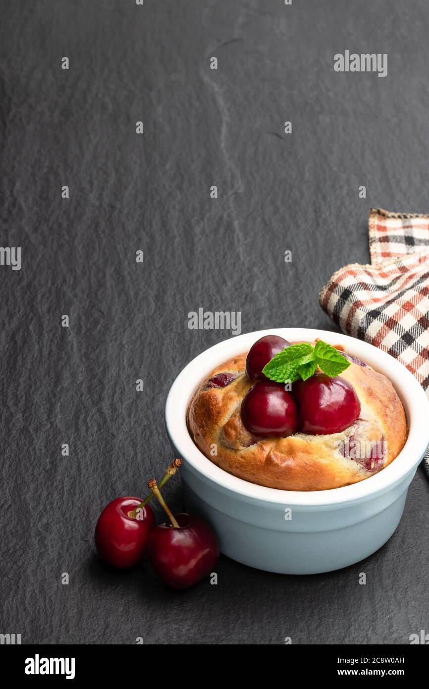 Muffin with cherry in small ceramic pot on black stone background Stock ...