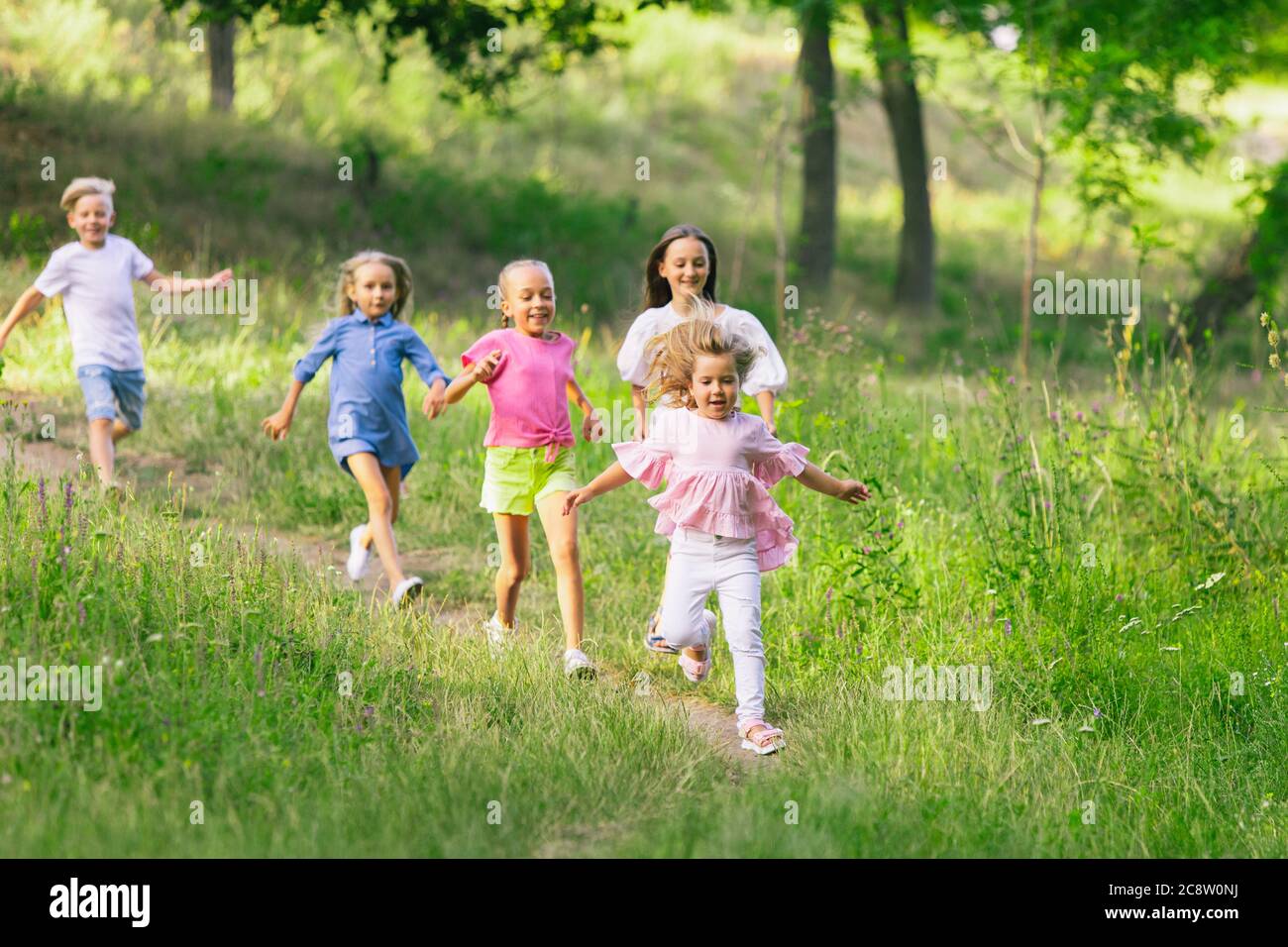 Kids, children running on meadow in summer's sunlight. Look happy ...