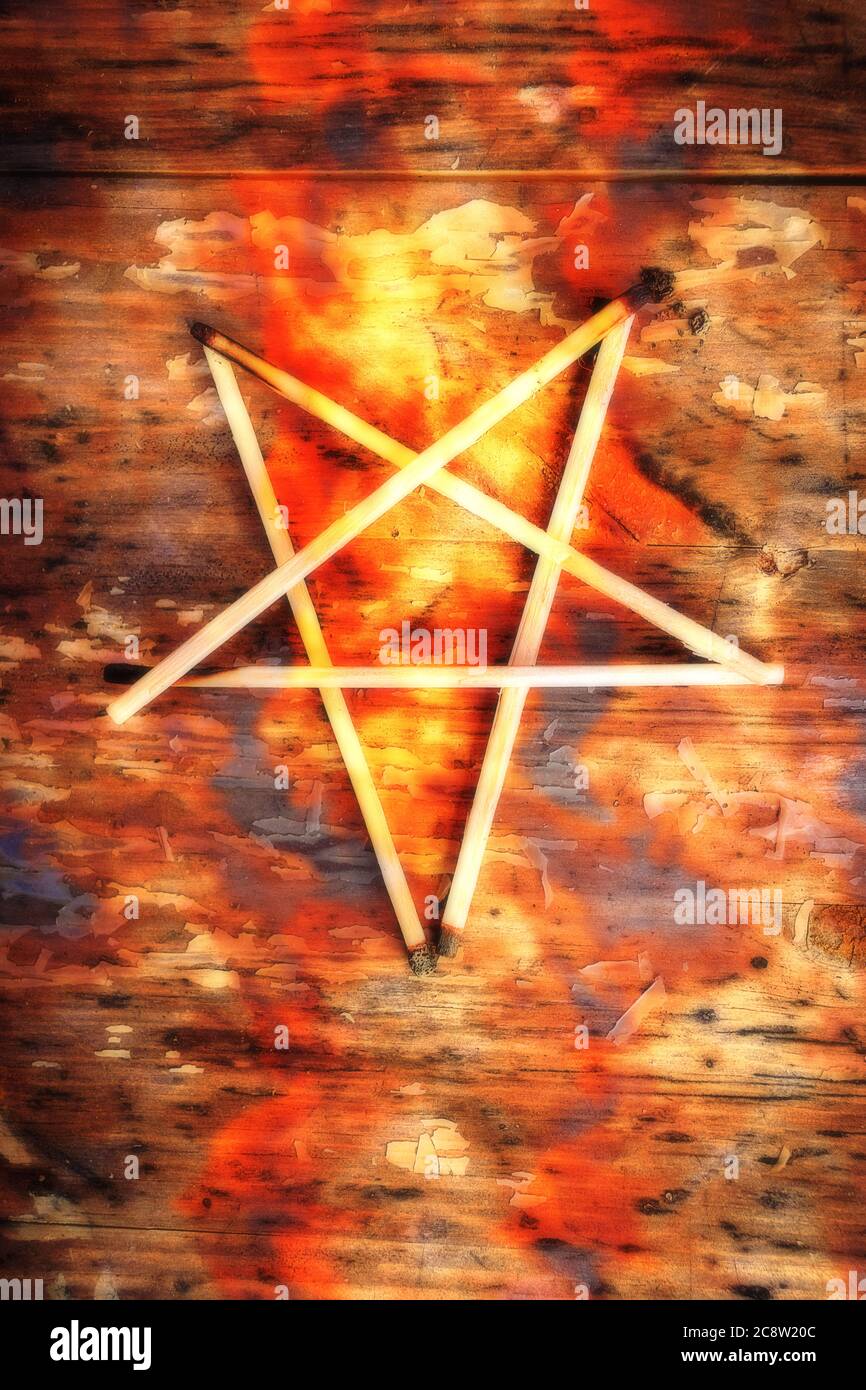 Pentagram symbol made out of matches with flames on a wooden background ...