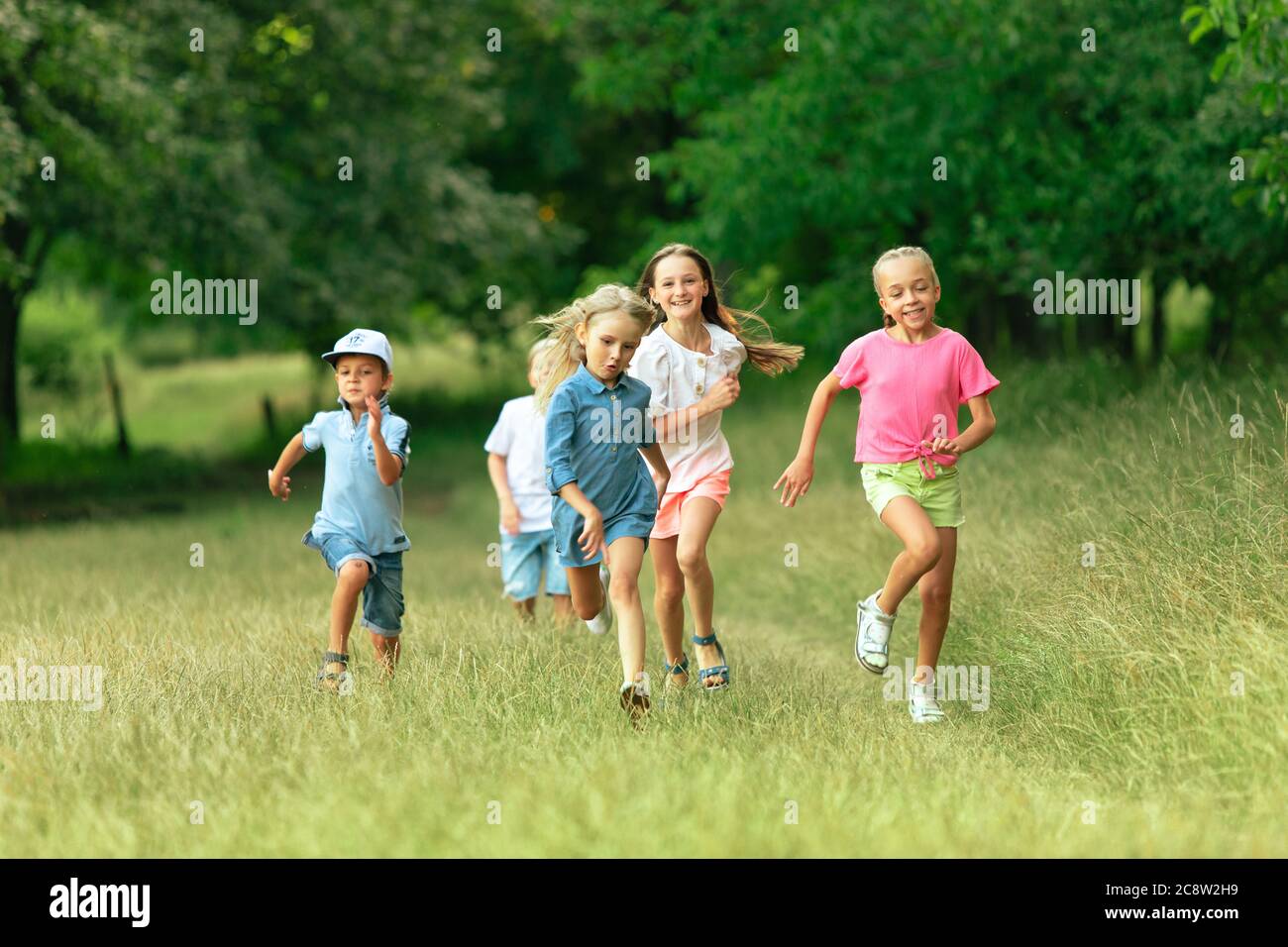 Kids, children running on meadow in summer's sunlight. Look happy ...