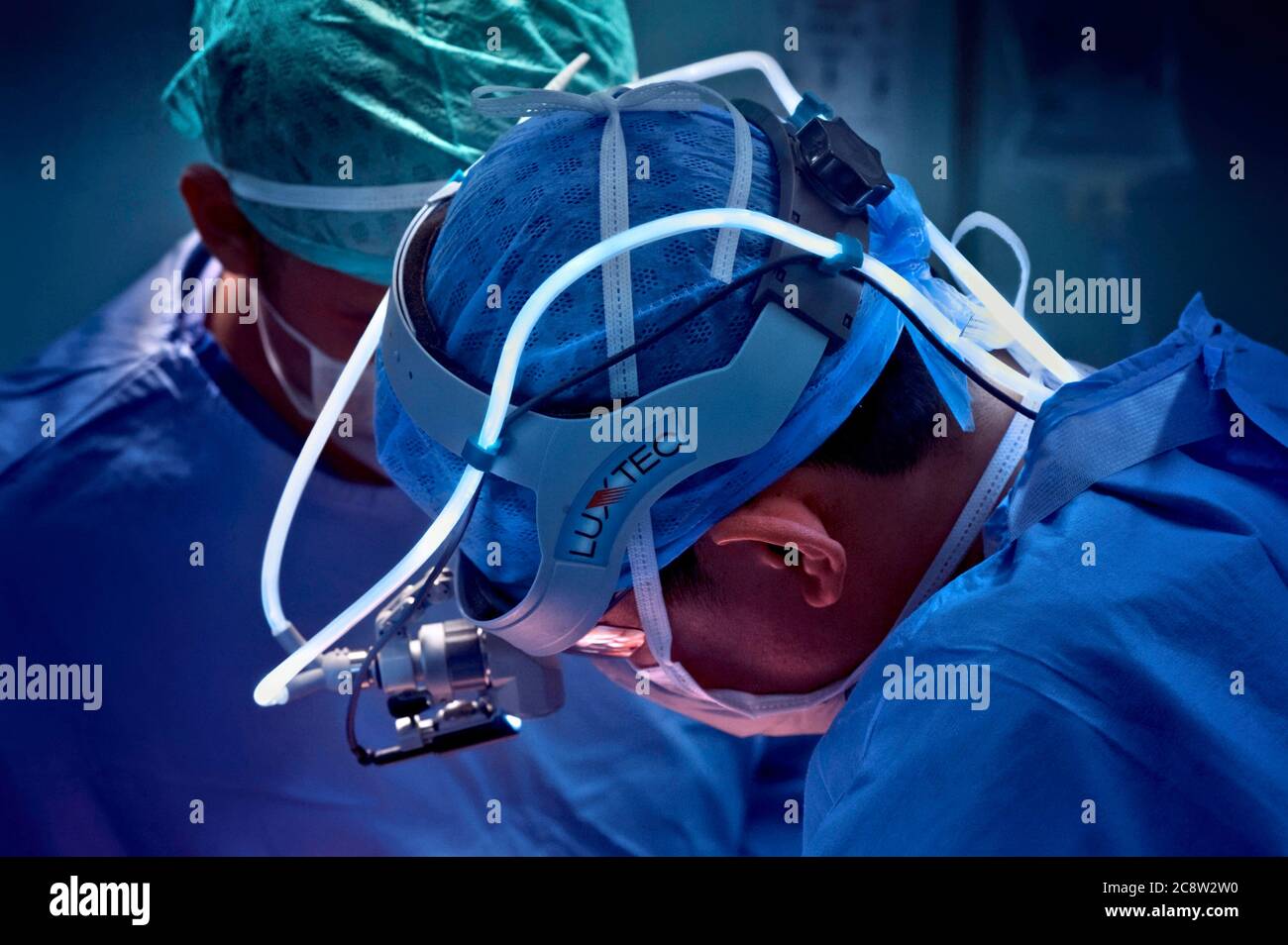 Surgeon performing a thoracic operation using a fibre-optic head-light ...