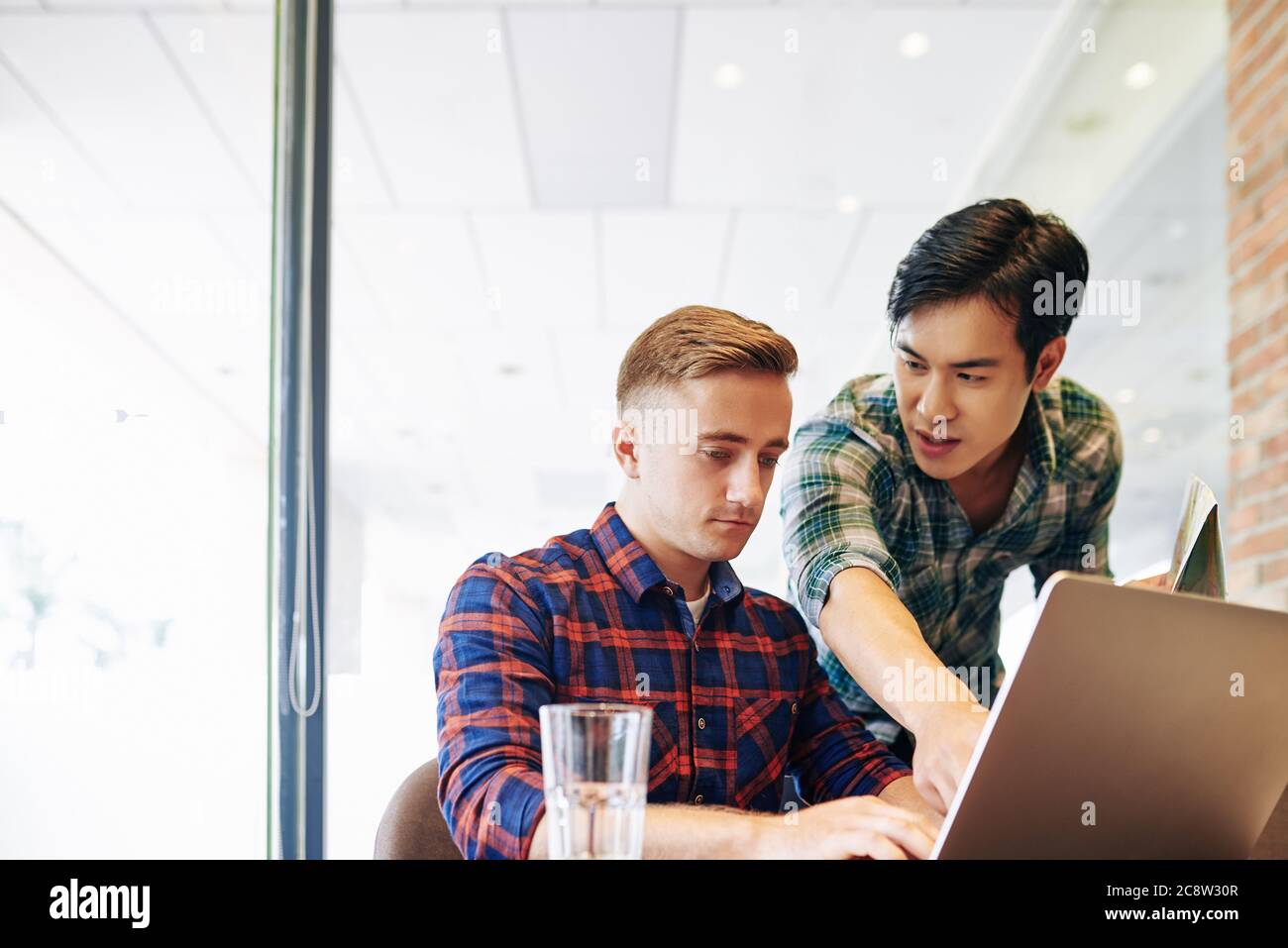 Handsome young Vietnamese man pointing at mistake of colleague in ...